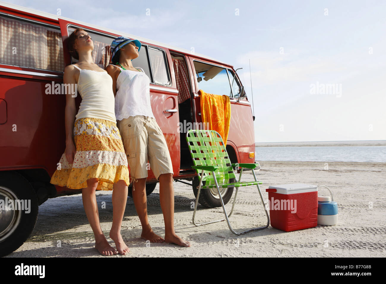 Young women leaning against van on beach Stock Photo - Alamy