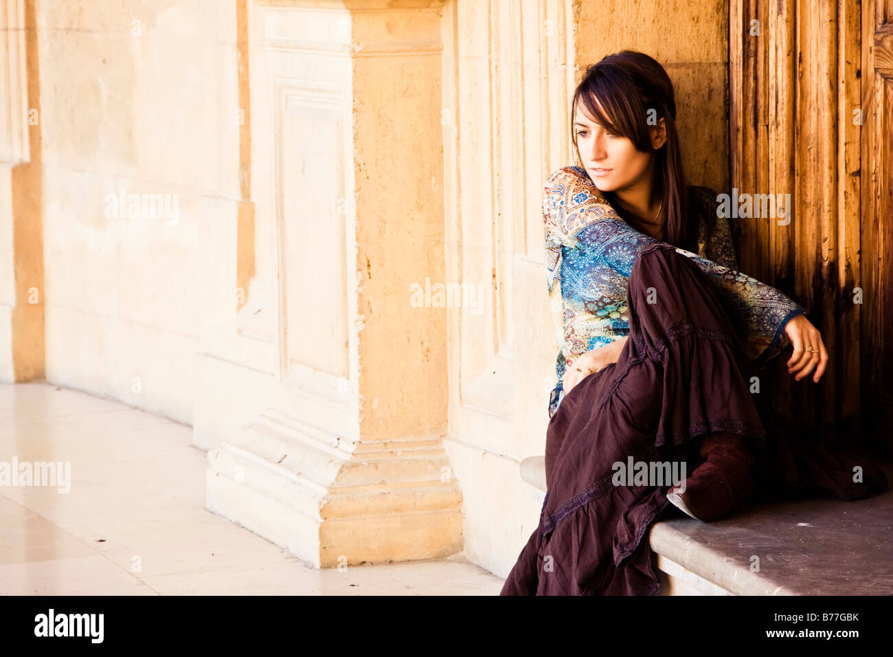 Thoughtful young woman sitted in old building Stock Photo - Alamy