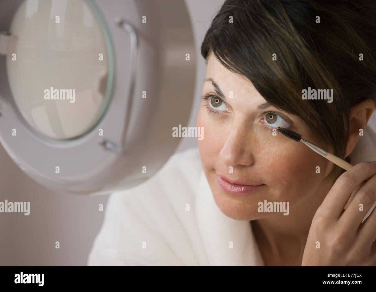 Woman applying makeup vanity mirror Stock Photo - Alamy