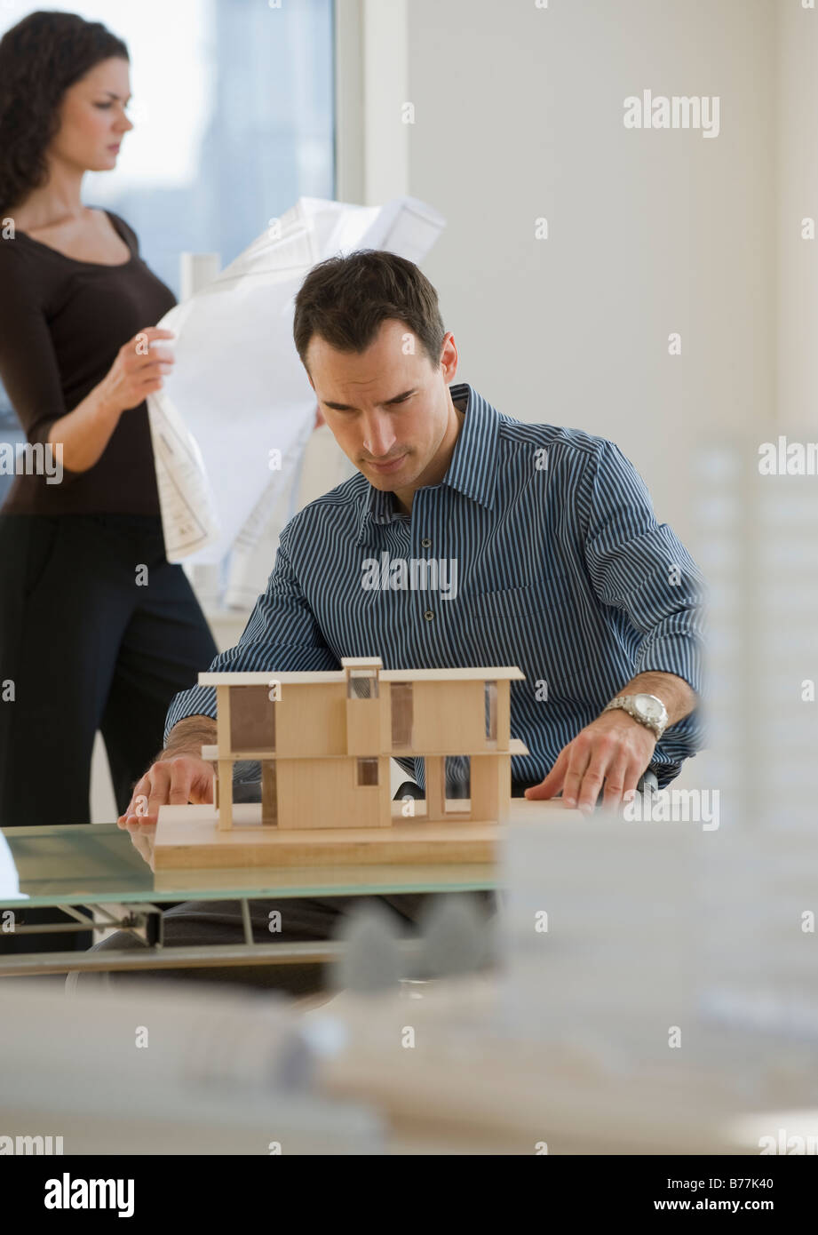 Architects working blueprints and building model Stock Photo - Alamy