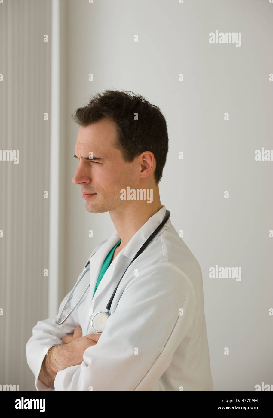 Male doctor looking out window pensively Stock Photo - Alamy