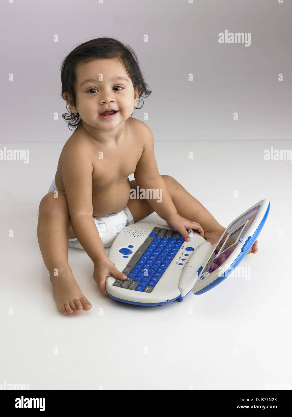 Indian baby girl wearing diaper playing with toy laptop MR#702O Stock ...