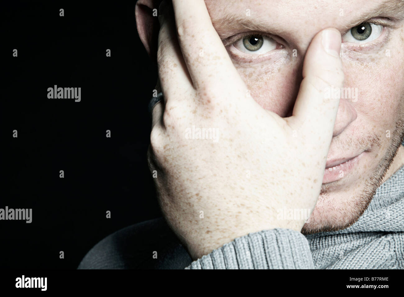 Young man holding a hand in front of his face Stock Photo - Alamy