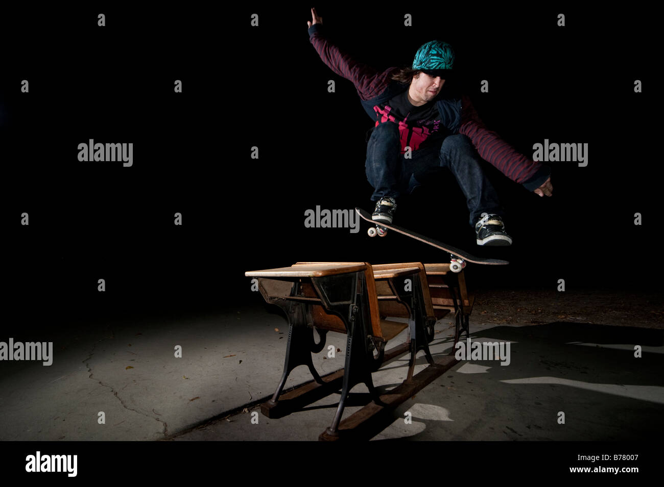 Skateboarder jumping over desks Stock Photo - Alamy