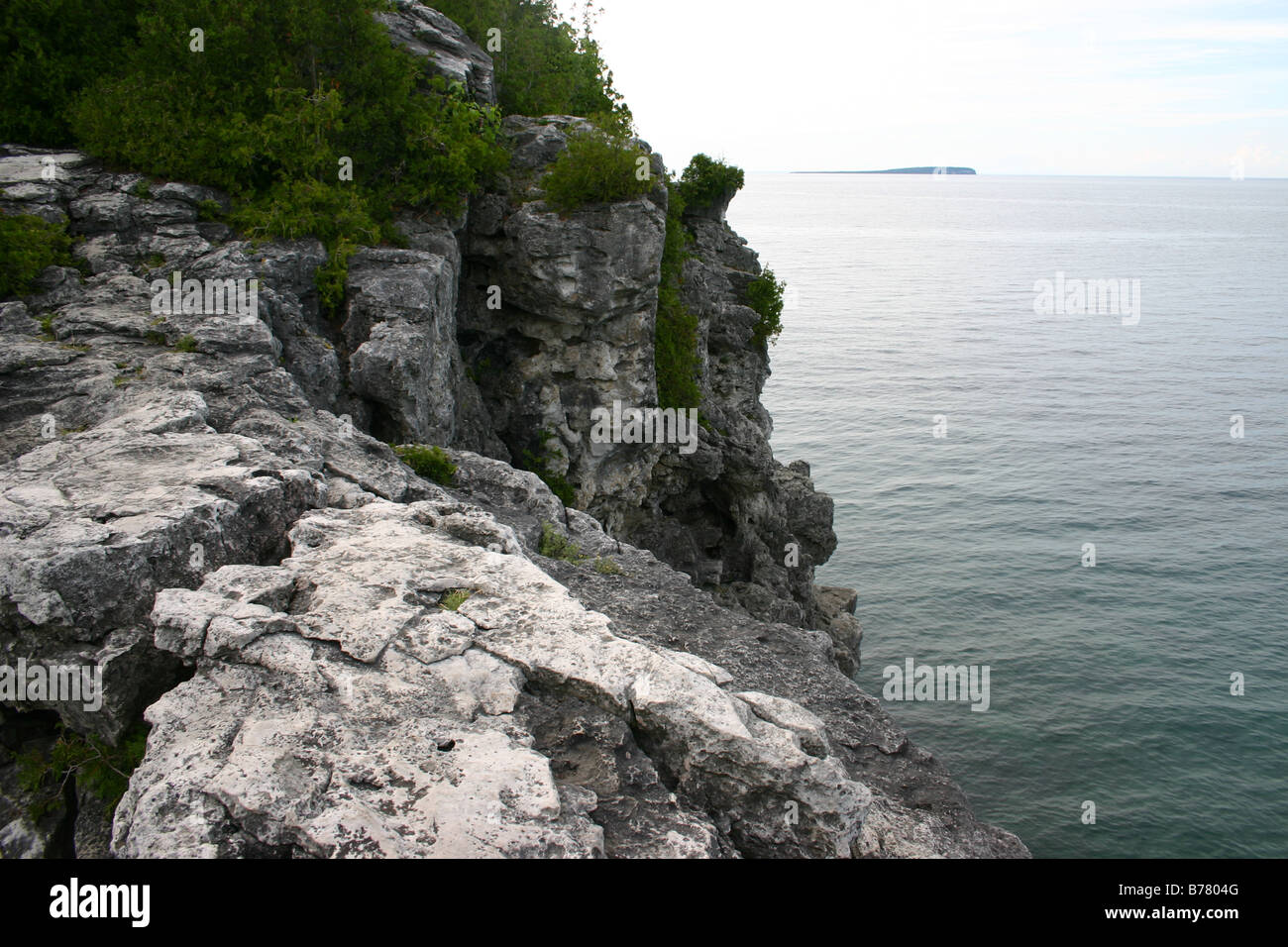 Jagged stone cliffs drop off into deep blue water in this image of the ...