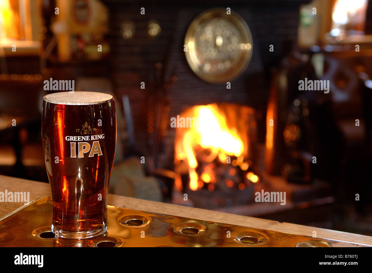 Pint of real ale with open fire behind in a traditional english country ...