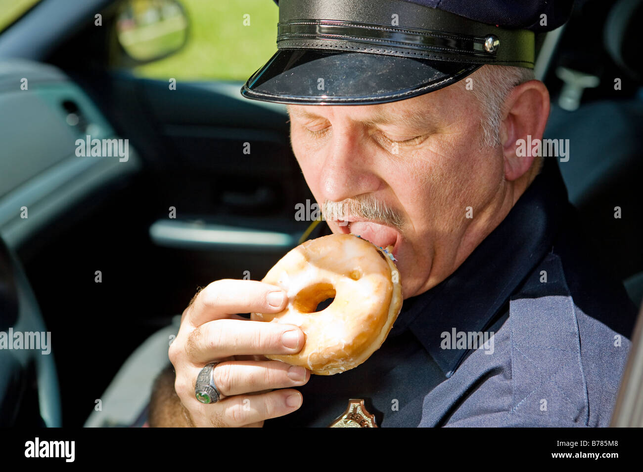 Police officer biting into a delicious glazed donut Stock Photo - Alamy