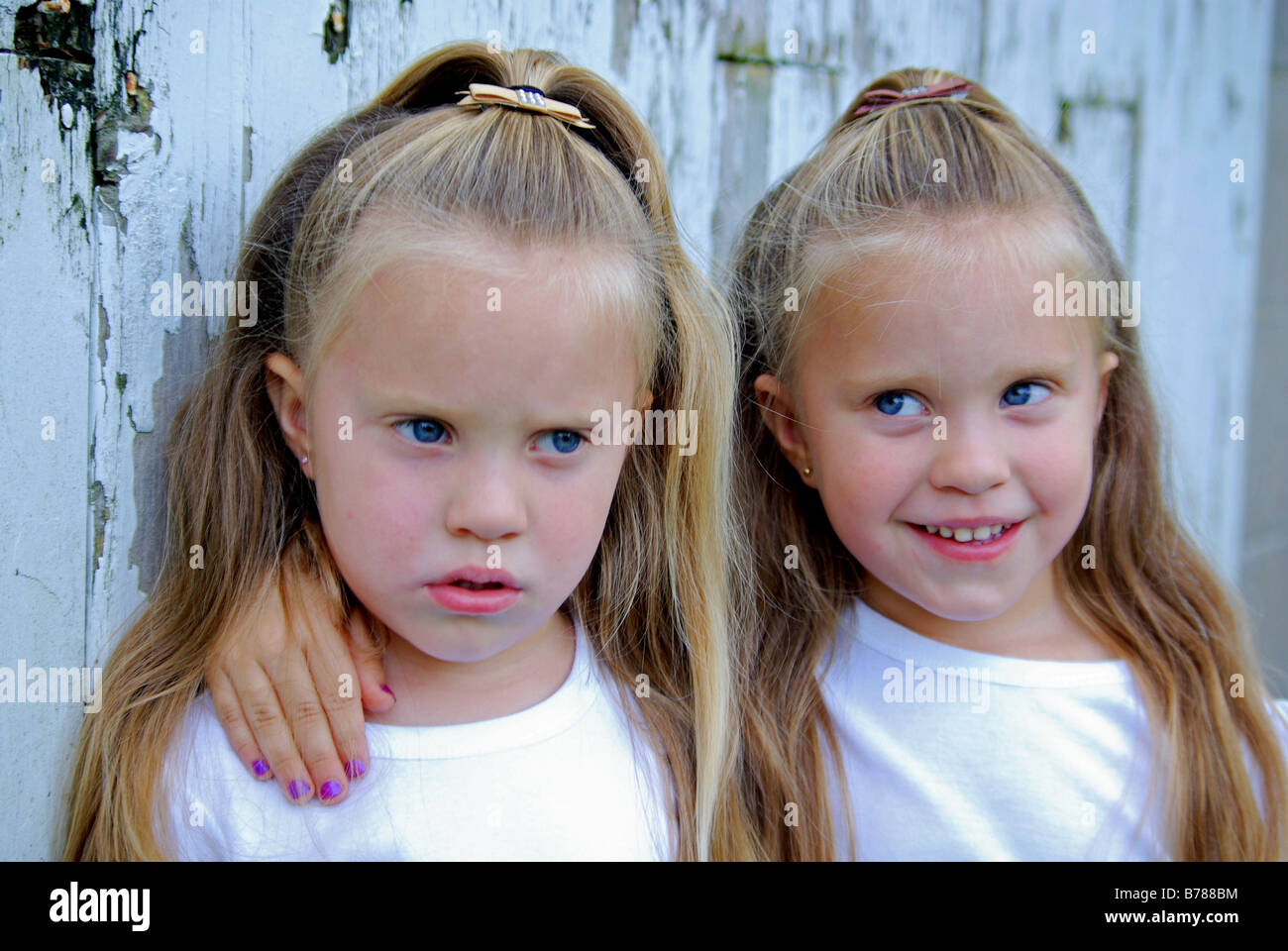 Twin four year old girls expressing the mixed emotions of happy and sad ...