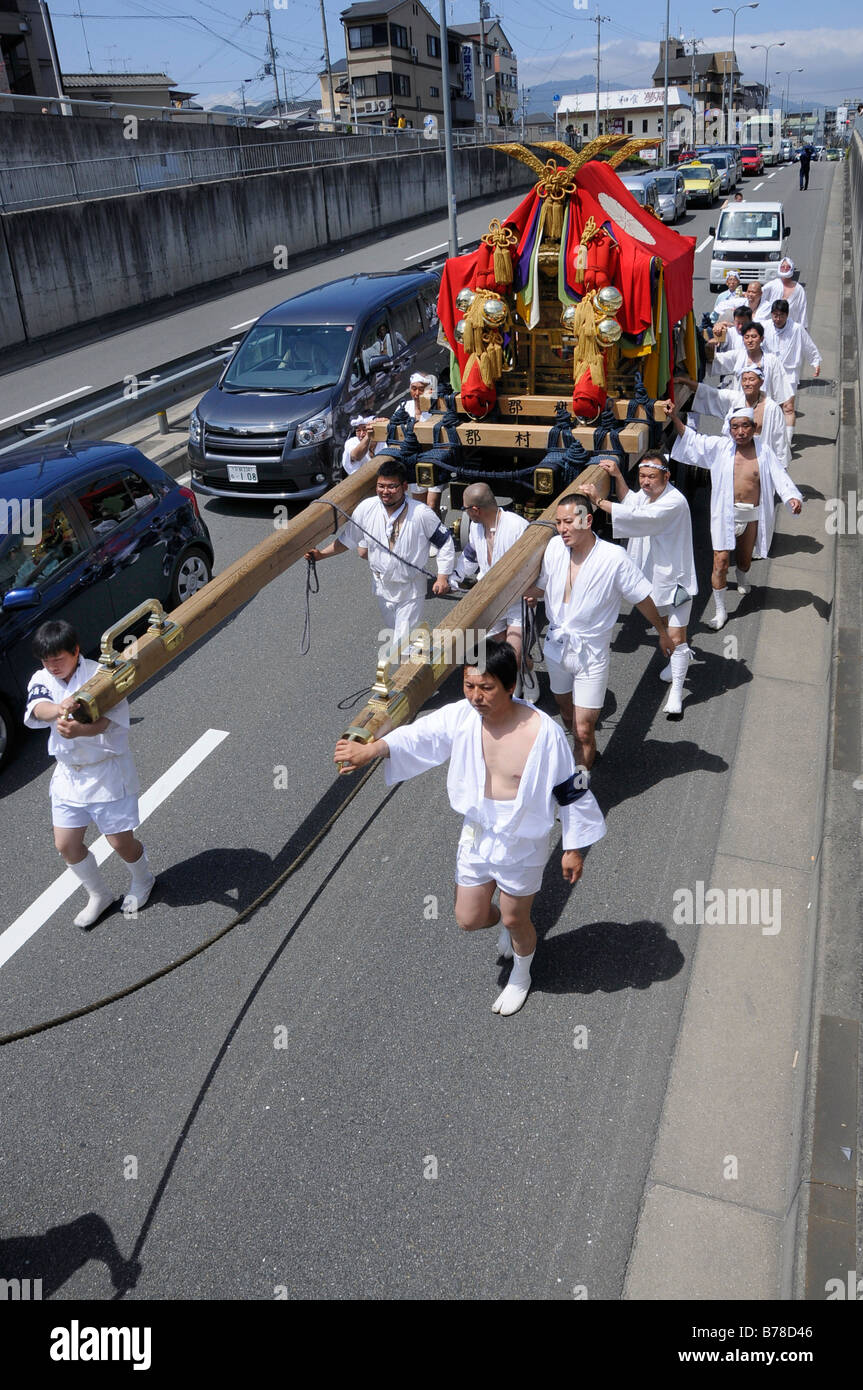Procession walking past cars on a wide road, leading to a subway ...
