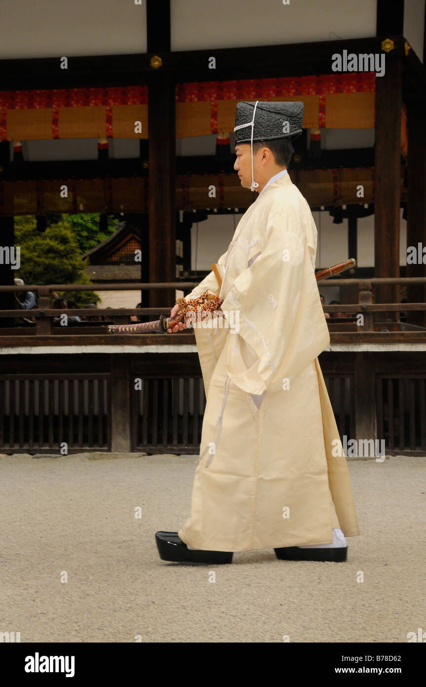 Shinto priest with a sword walking toward the temple gate after ...