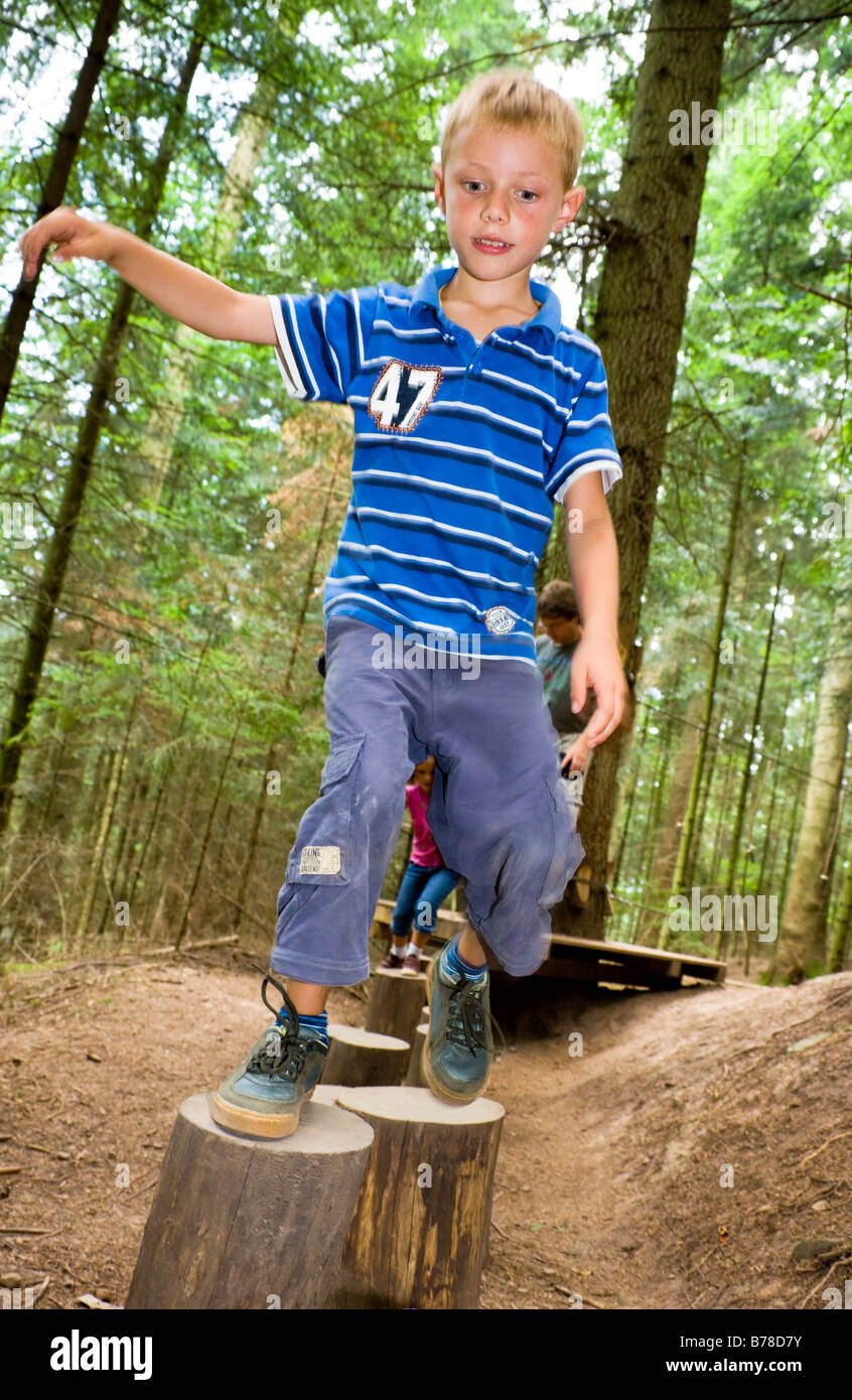 6-year-old boy balancing on a path of tree trunks Stock Photo - Alamy