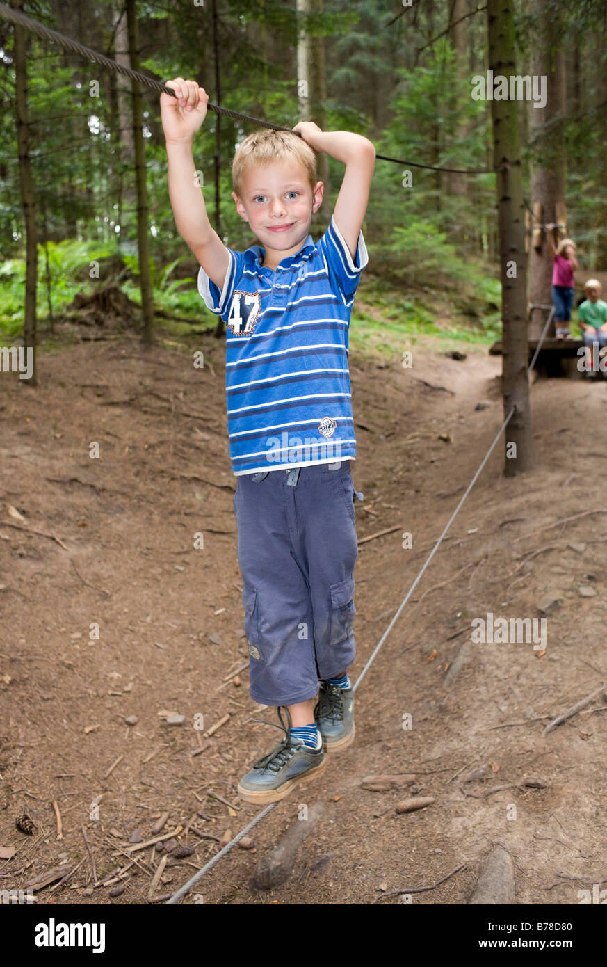6-year-old boy balancing on a rope in a forest Stock Photo - Alamy