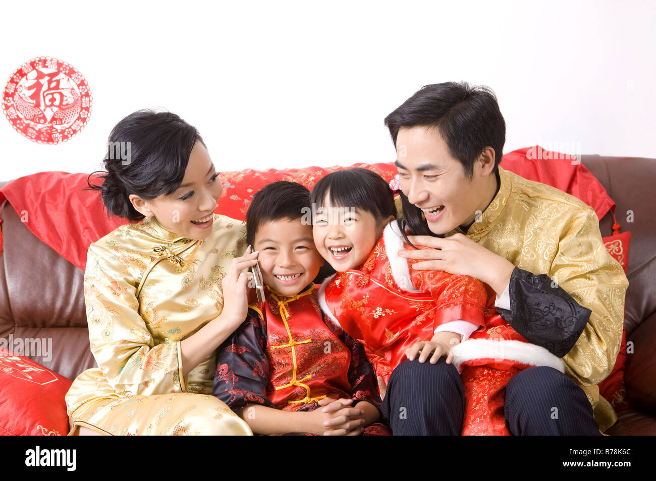 A family in traditional clothes sitting on the sofa and smiling happily ...