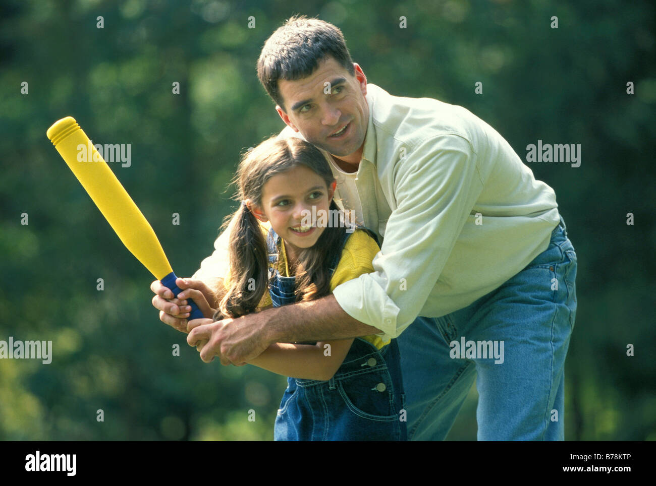 Man helps girl learn baseball Stock Photo - Alamy