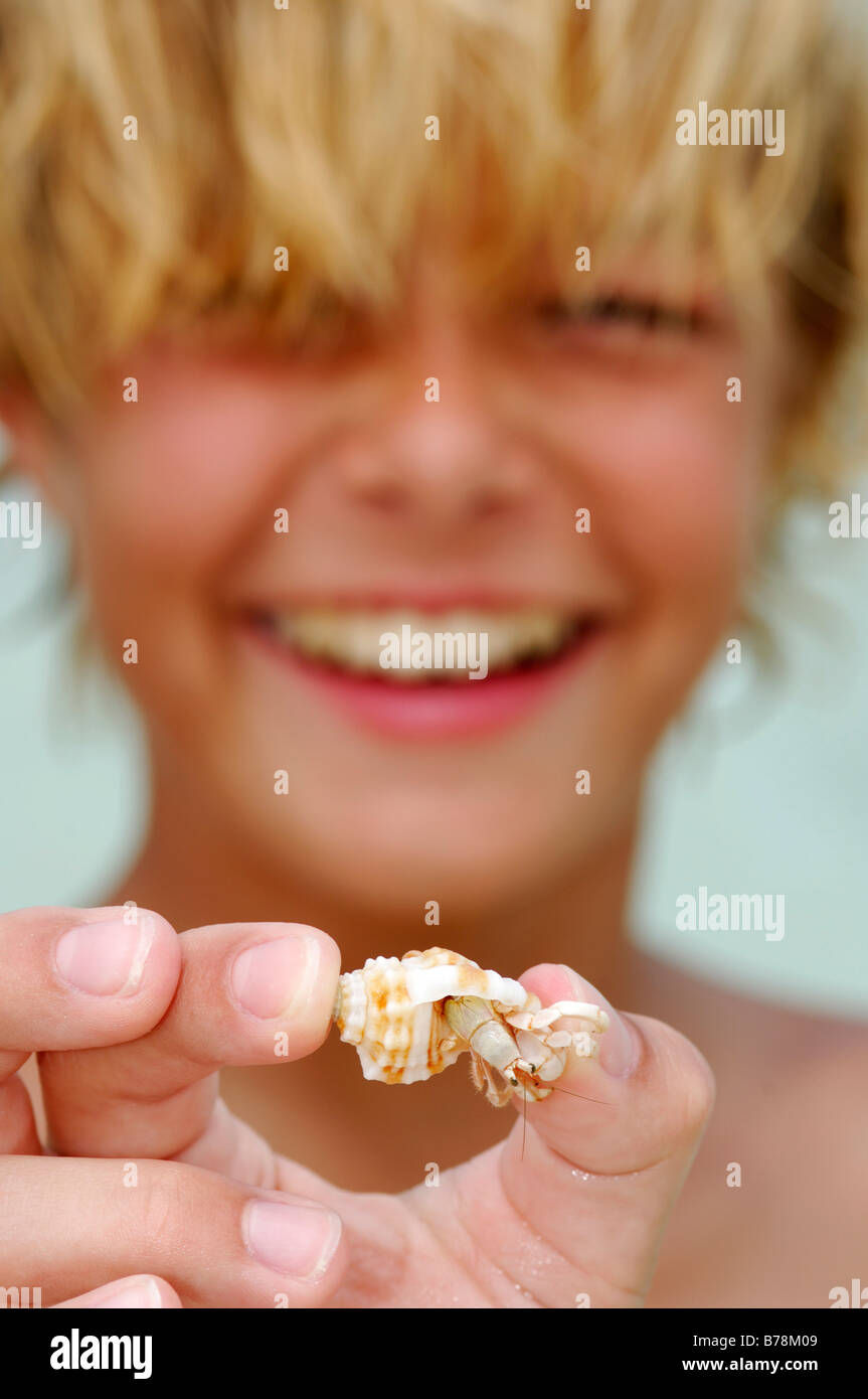 Young boy with a hermit crab, laughing, Baros Resort, The Maldives ...