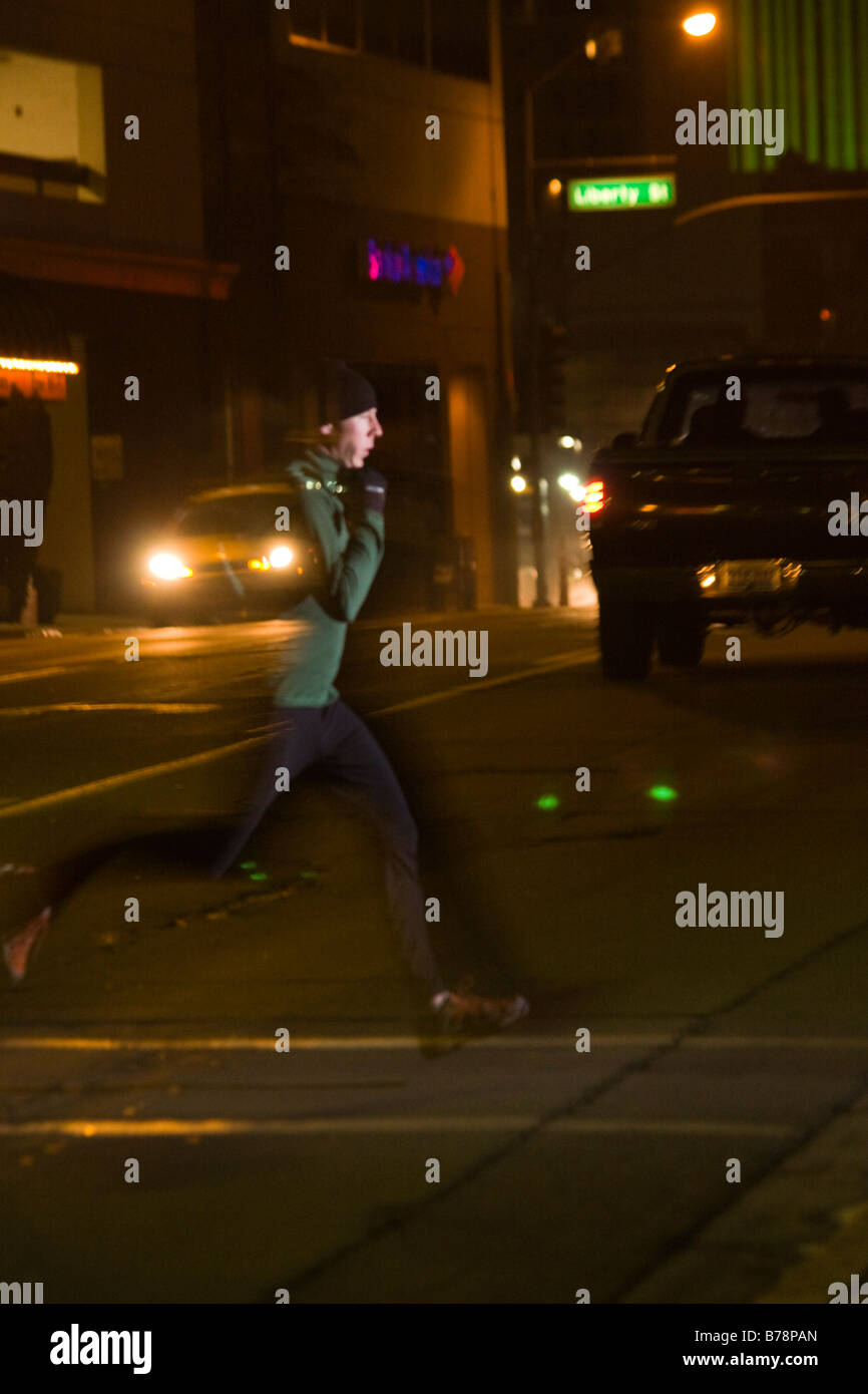 A man running along the road at night under the lights of Reno in ...