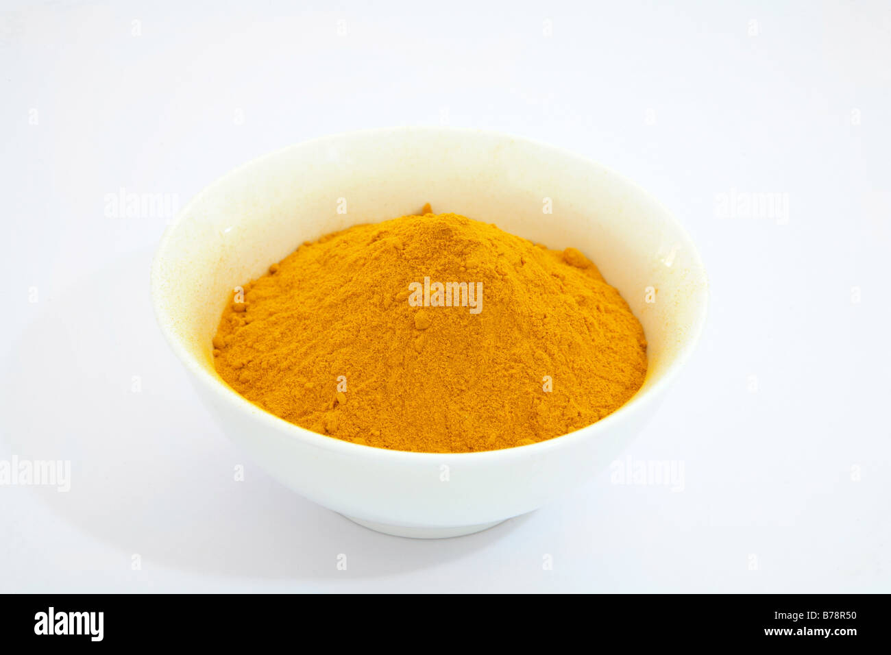 A white bowl of ground turmeric on a plain background Stock Photo - Alamy