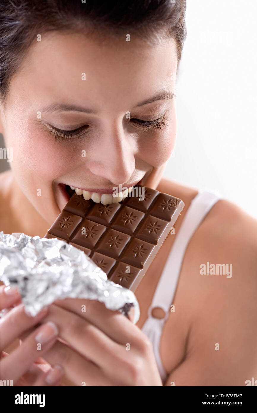 Young woman biting into chocolate bar, close up Stock Photo - Alamy