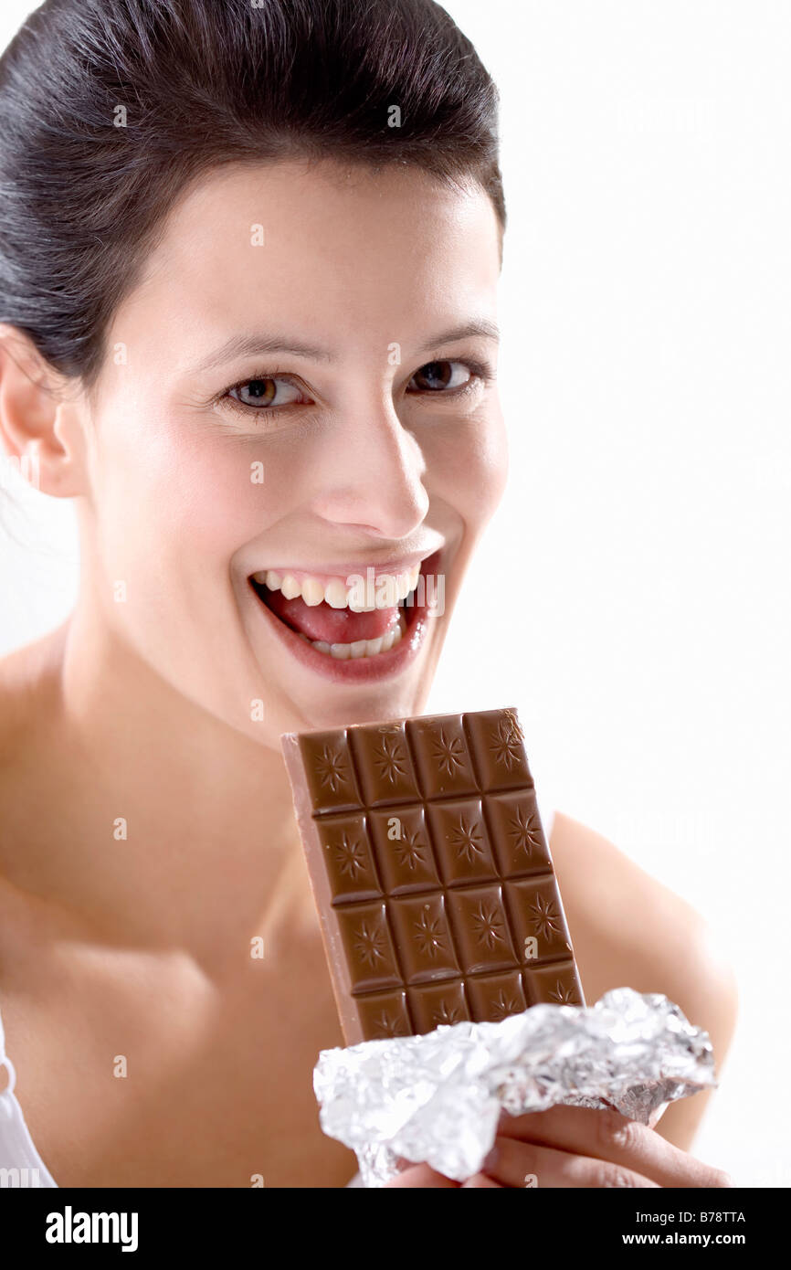 Young woman holding chocolate bar, smiling Stock Photo - Alamy