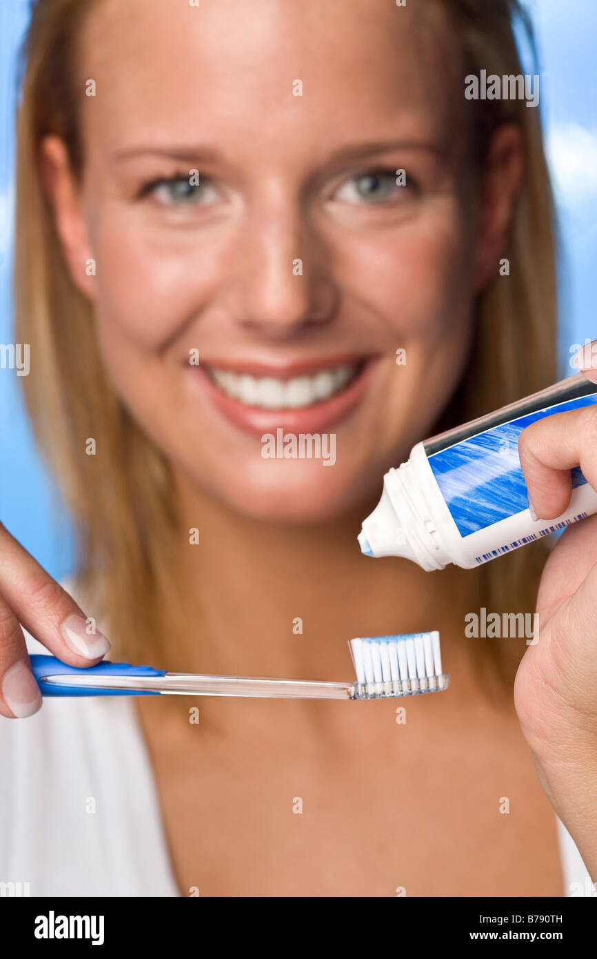 Young woman putting toothpaste on brush, portrait Stock Photo - Alamy