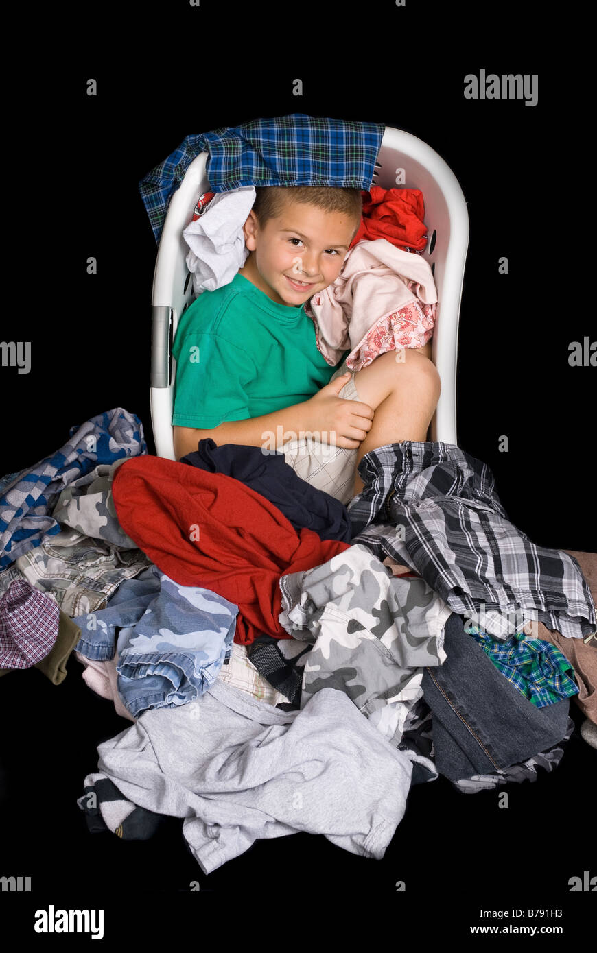 A young boy curls up in a warm clothing basket full of freshly dried ...