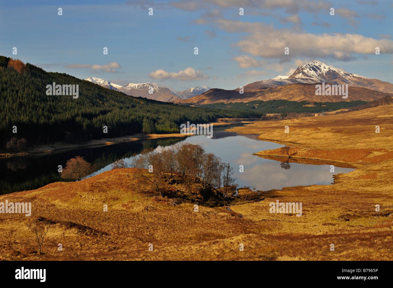 The broad River Garry flanked by trees and with hills and snow capped ...