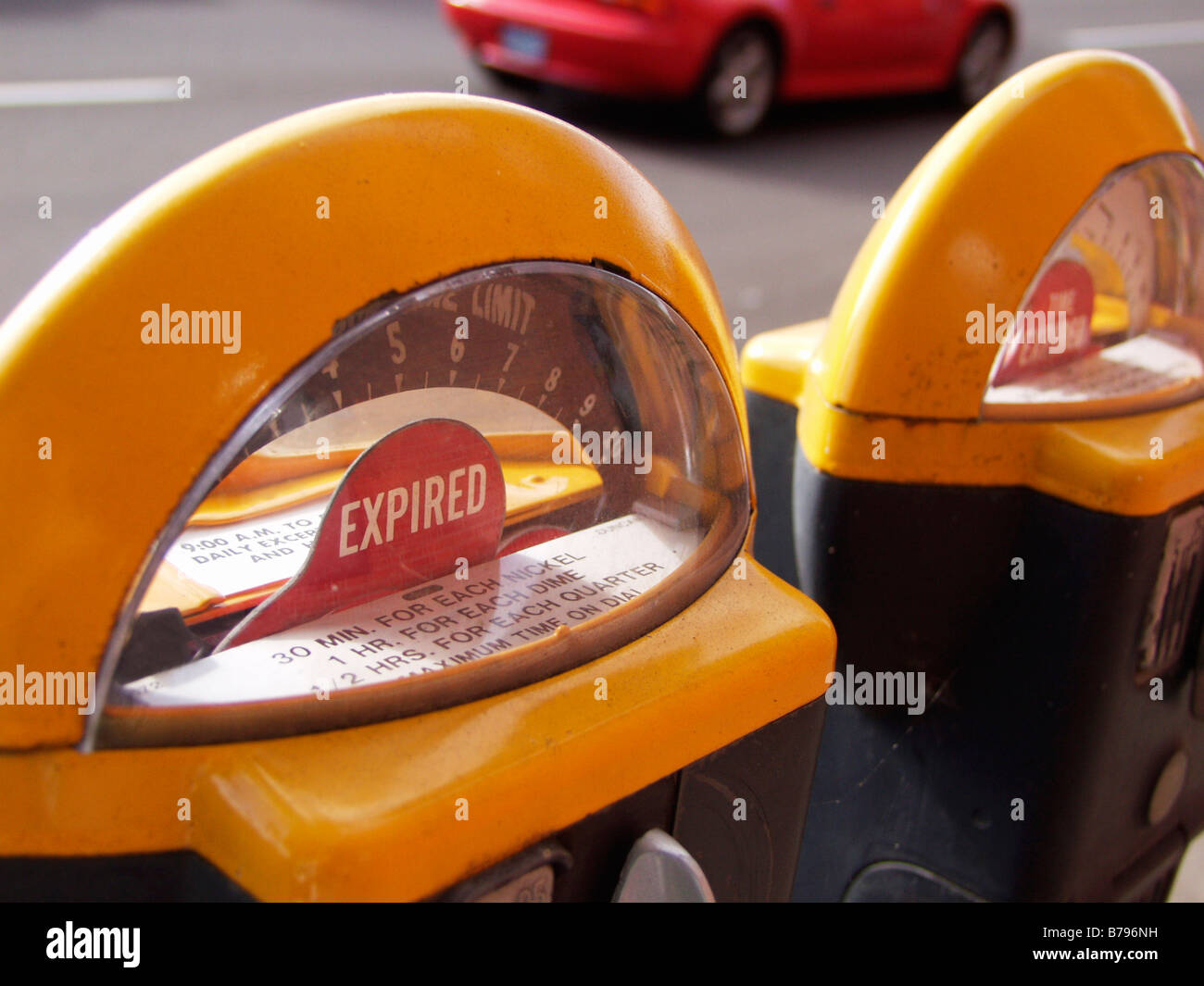 Expired parking meter with red car driving past on road in downtown ...