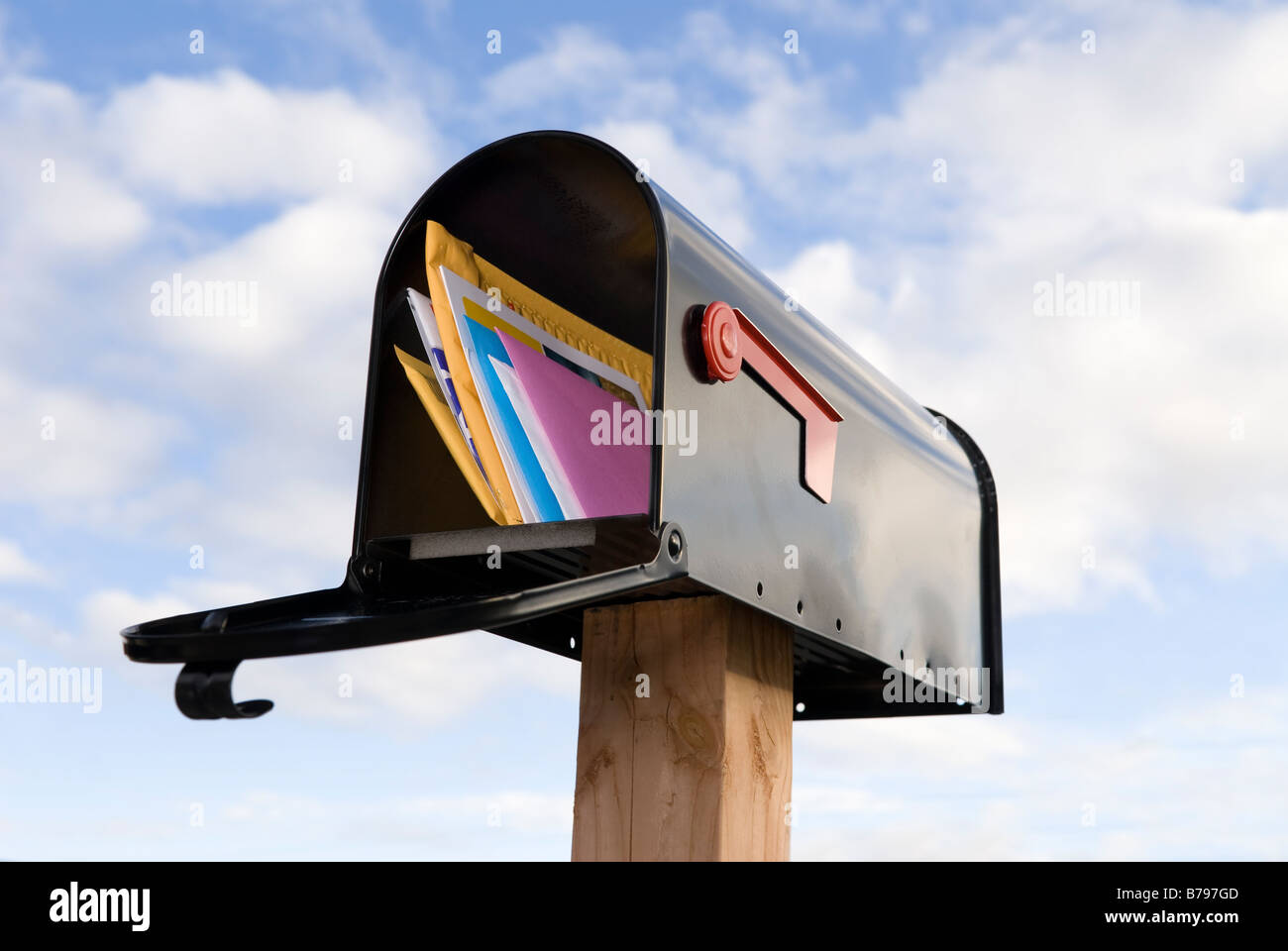 A mailbox full of mail against a blue and puffy white cloud sky Stock ...