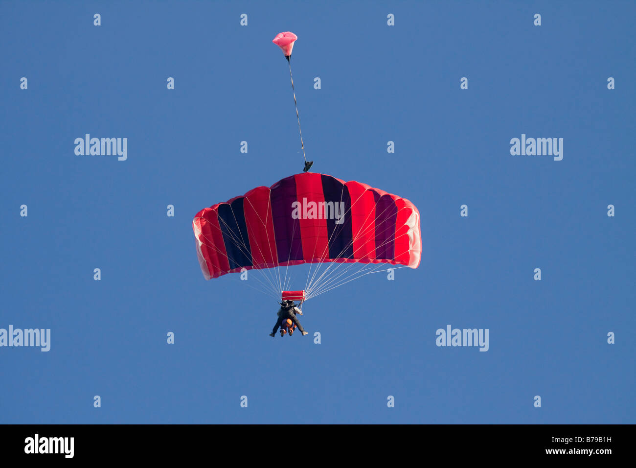 TANDEM PARACHUTING IN ENGLAND A RED STRIPED PARACHUTE CARRYING TWO ...