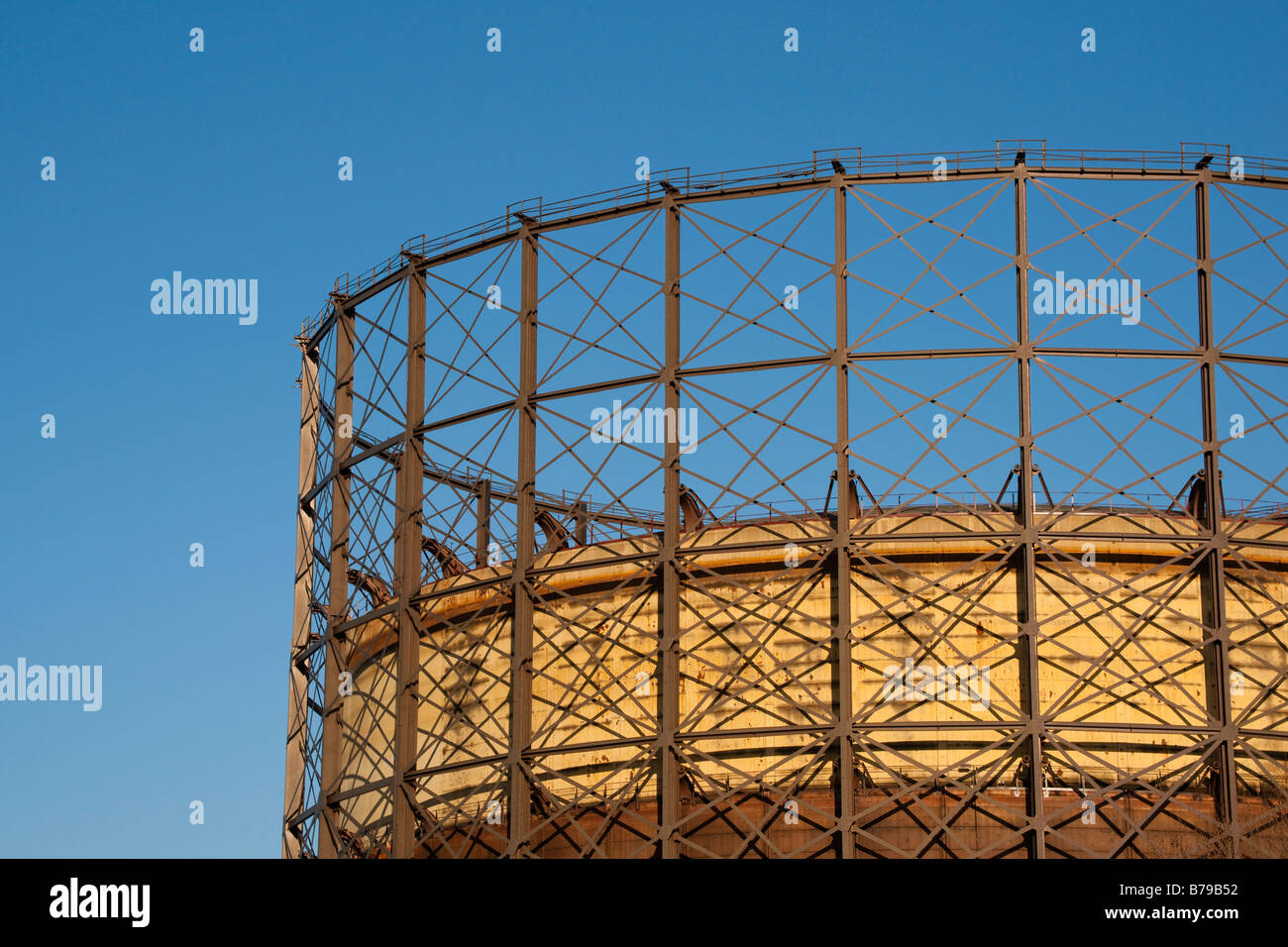 Detail of gas reservoir structure against clear blue sky under golden ...