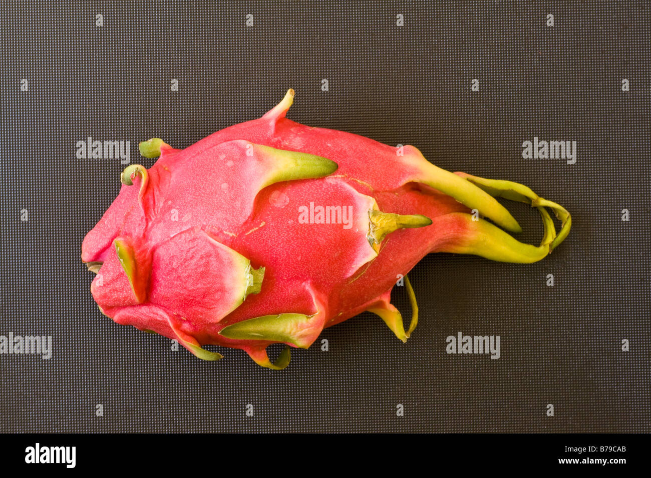 A whole dragonfruit on a black cutting board Stock Photo - Alamy