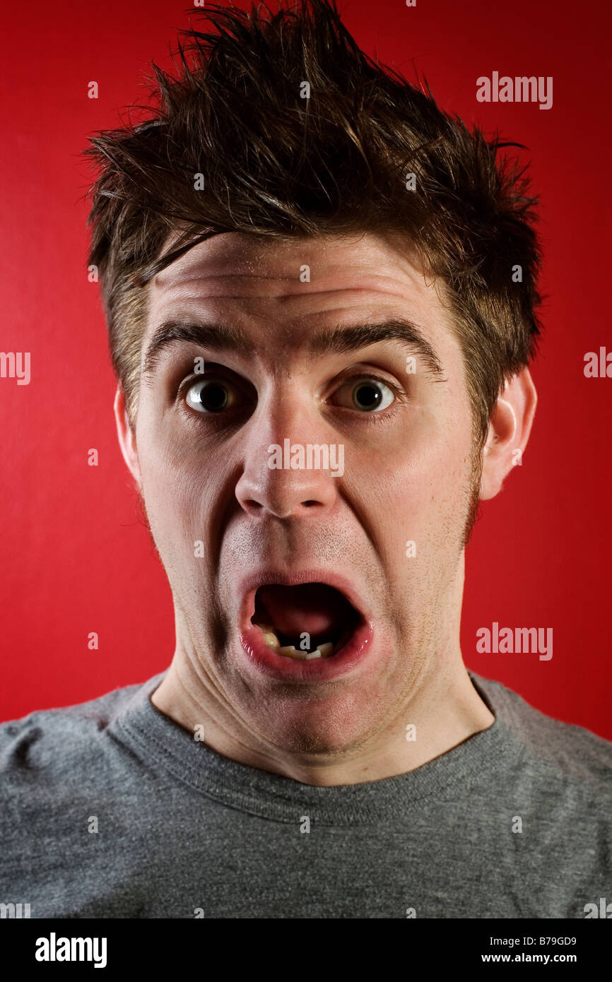 Young man with shocked expression against red background Stock Photo ...