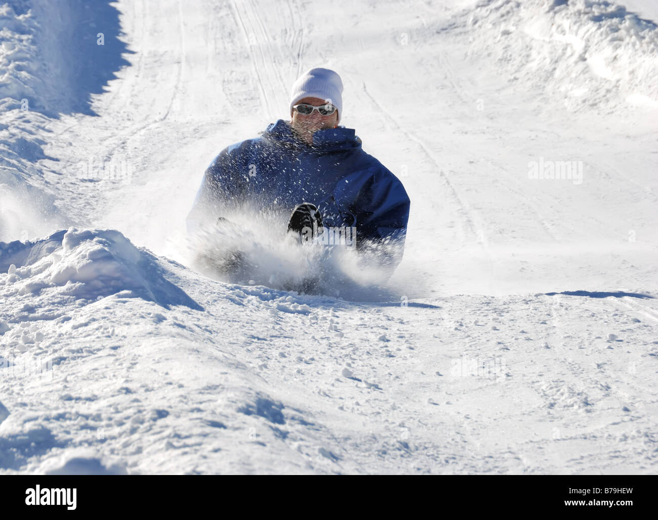 man braking while sledding fast down the hill with snow background ...