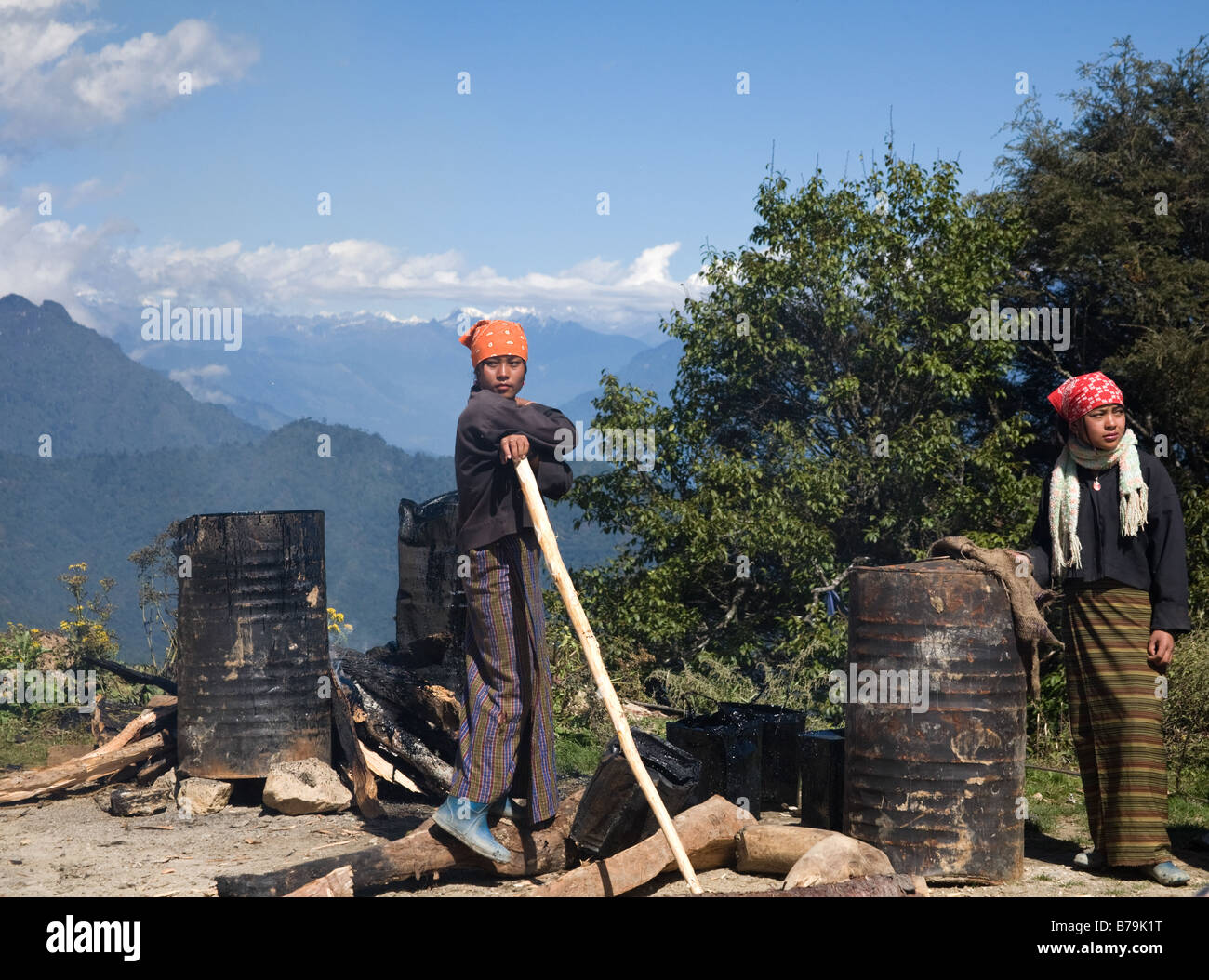 Two young women, perhaps Nepali, working with barrels of tar on the ...