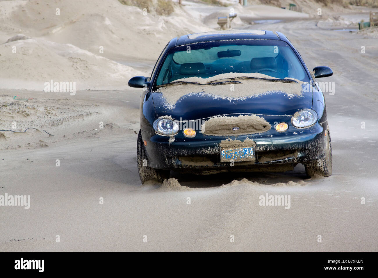Sand covers a residential street and automobile after a large storm on ...