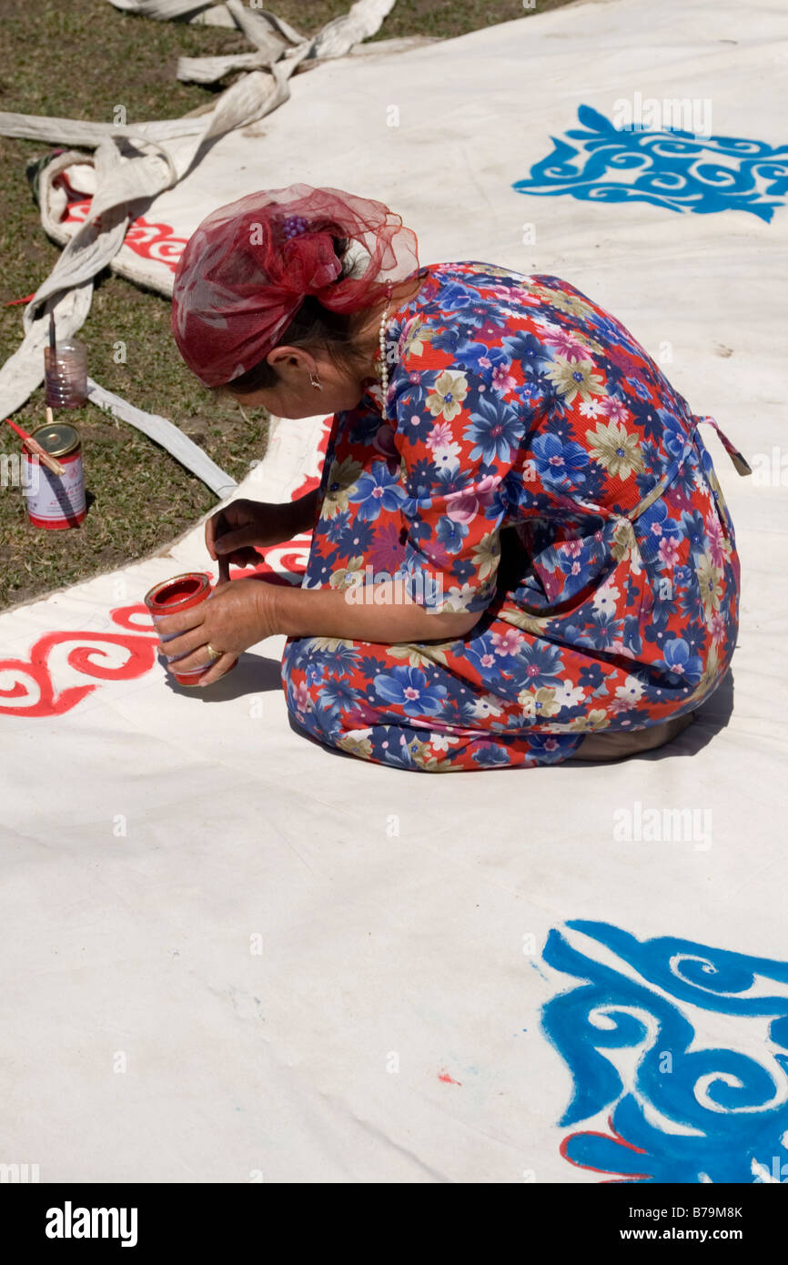 A Mongol nomad painting the patterns on a sheeting for her yurt Stock ...