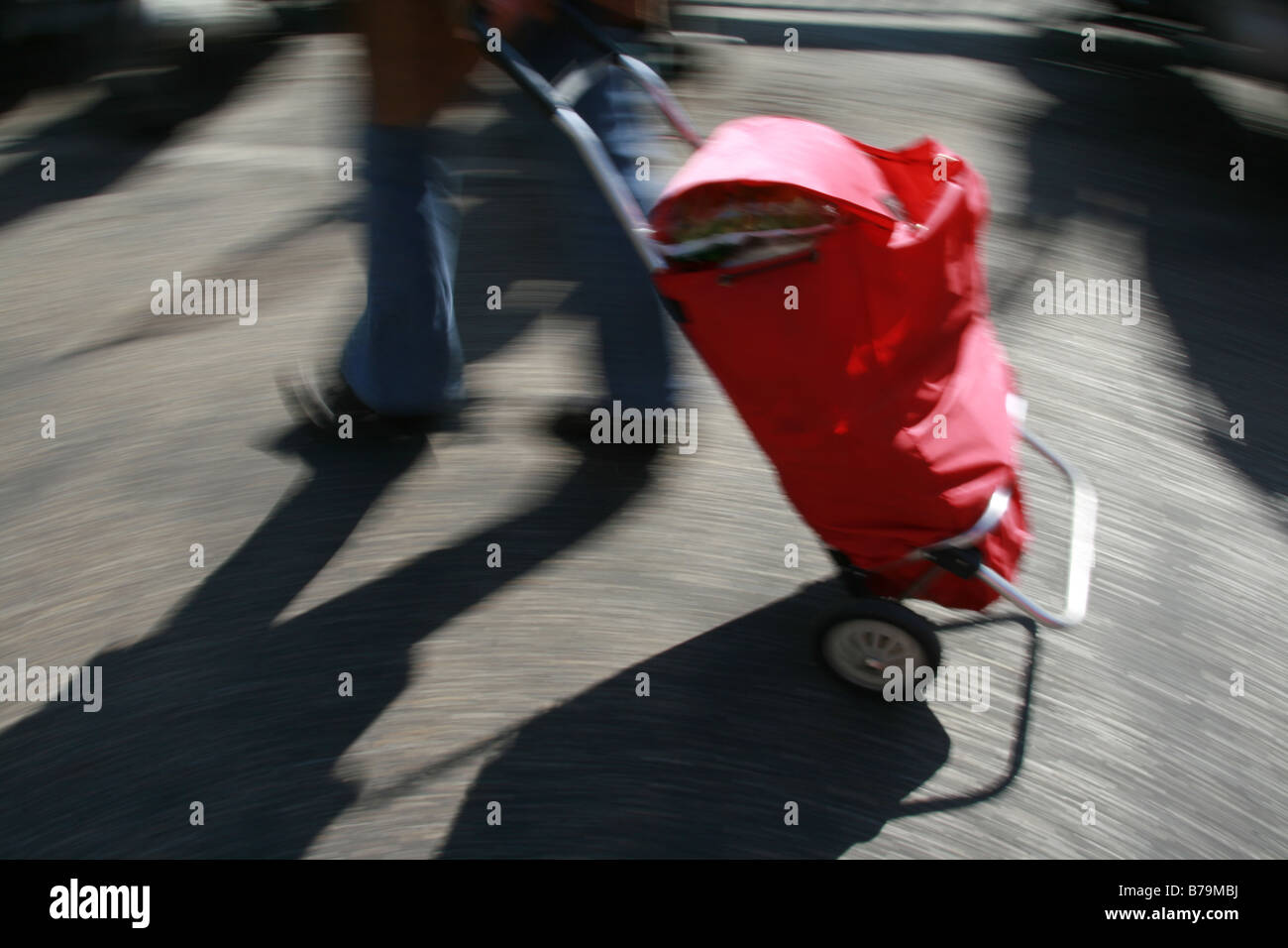 person pulling full heavy shopping trolley in street Stock Photo - Alamy