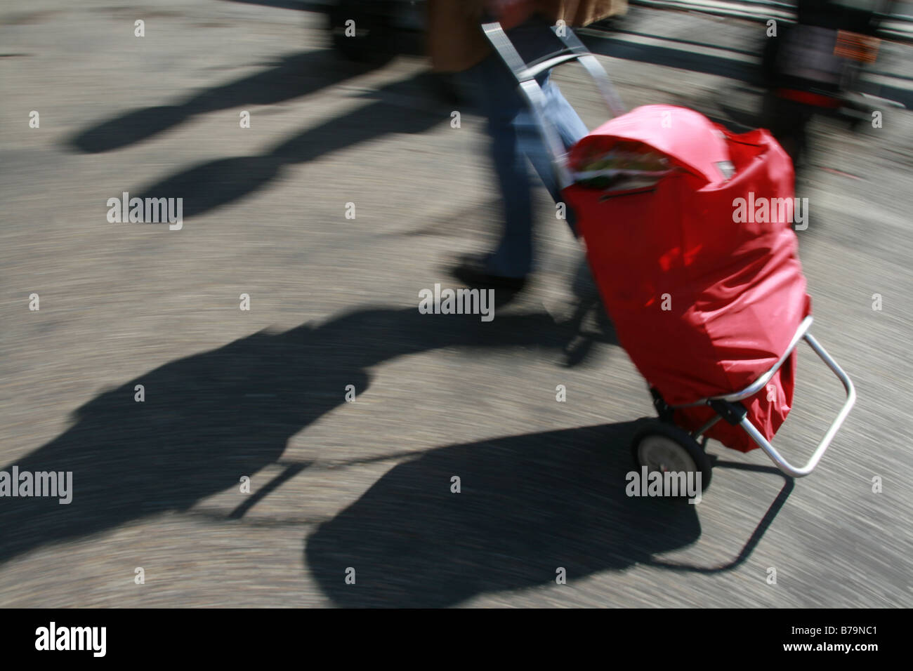 person pulling full heavy shopping trolley in street Stock Photo - Alamy