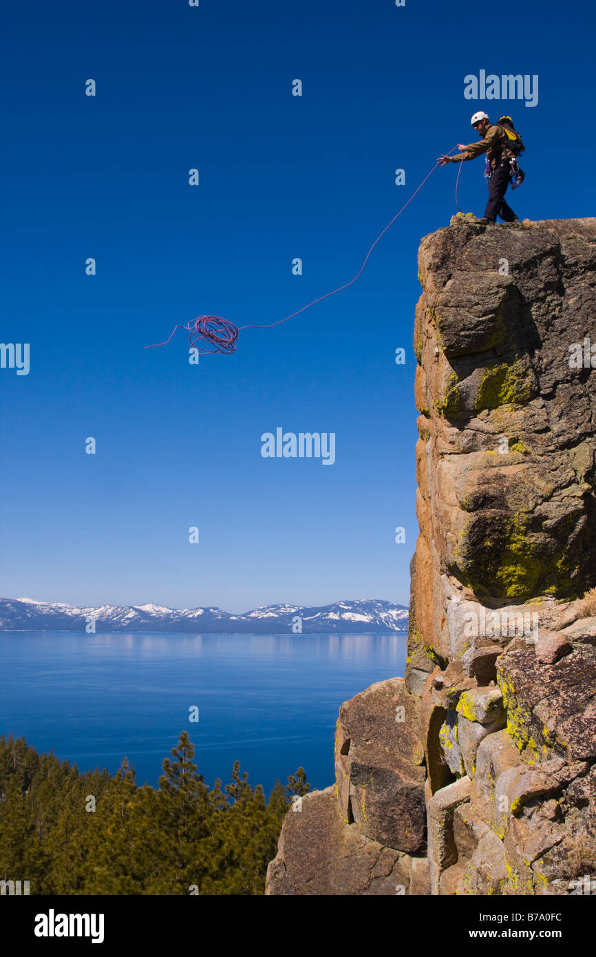 A mountaineer throwing a rope off a cliff above Lake Tahoe and the ...