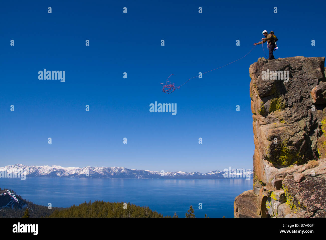 A mountaineer throwing a rope off a cliff above Lake Tahoe and the ...