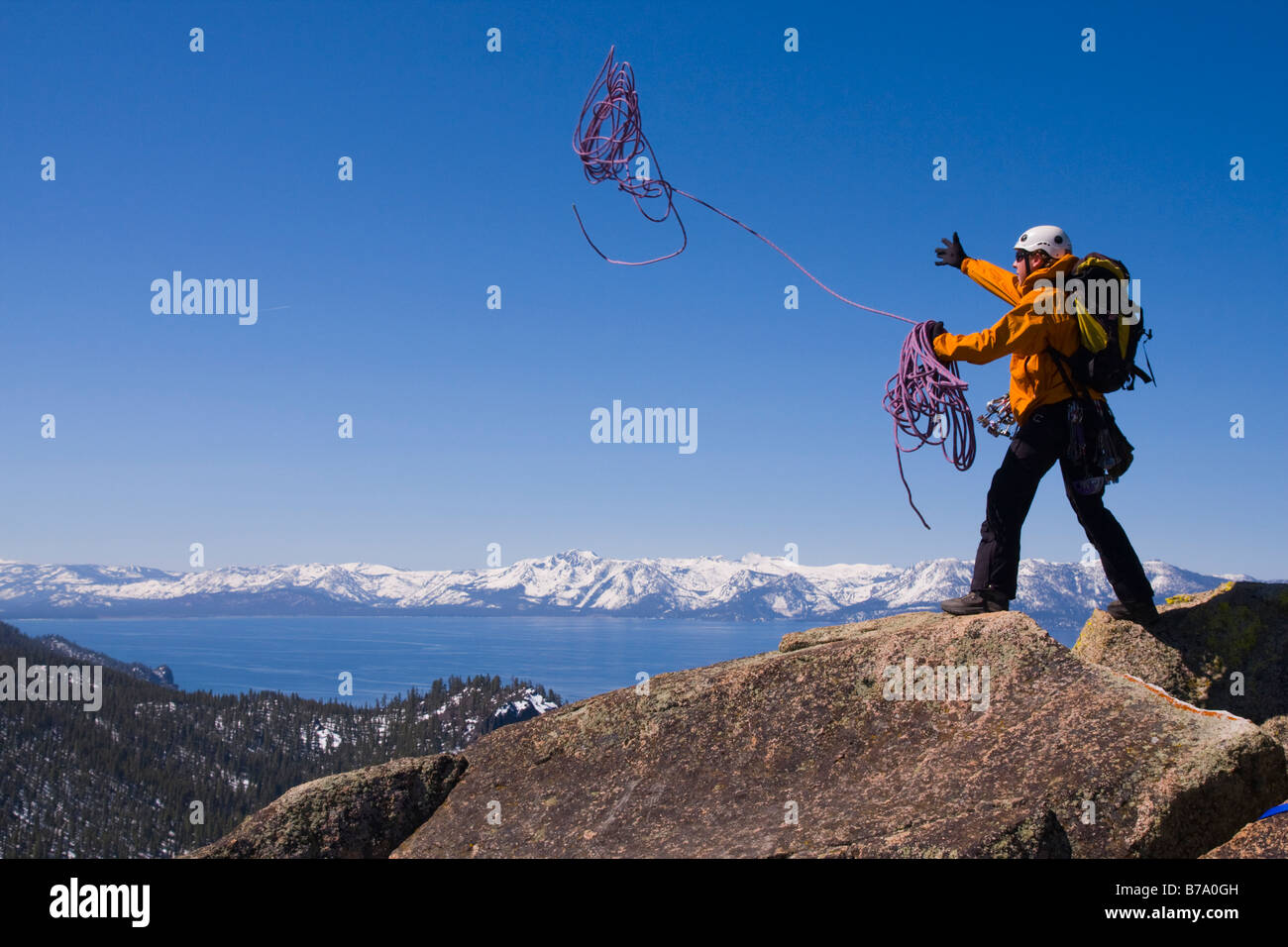 A mountaineer throwing a rope off a cliff above Lake Tahoe and the ...