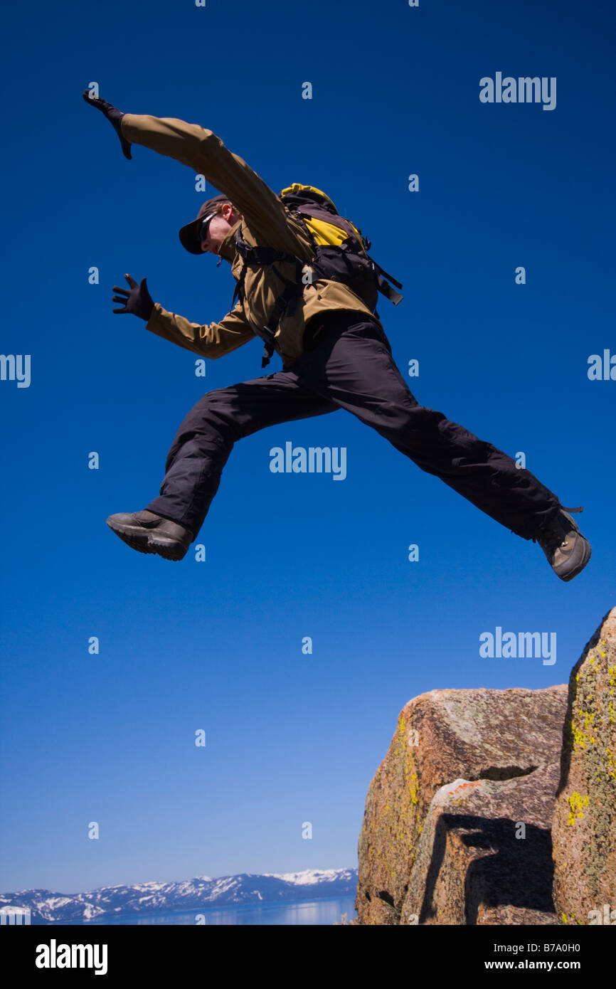 A man jumping from rock to rock while hiking in the Sierra mountains ...