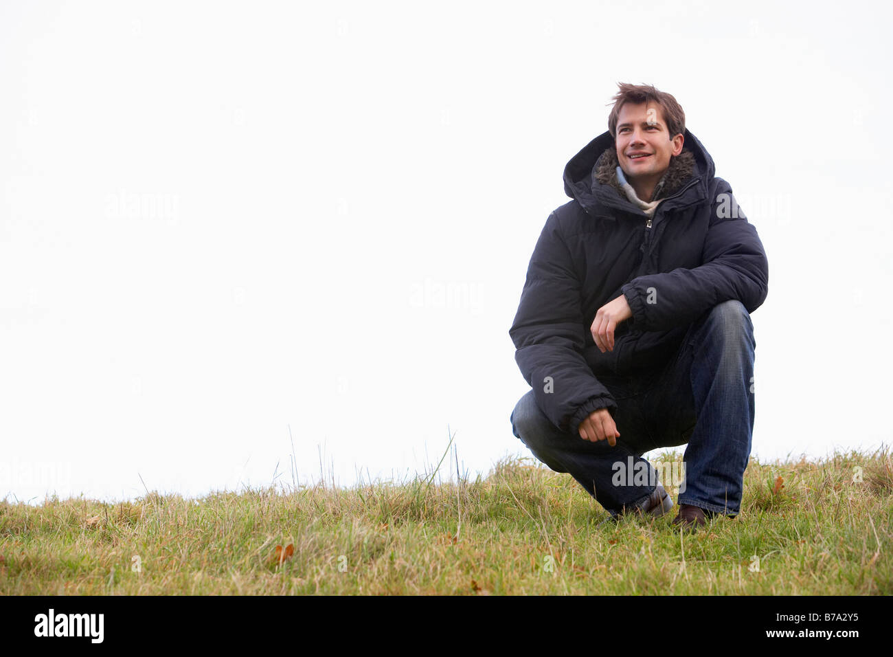 Man Crouching In Park Stock Photo - Alamy