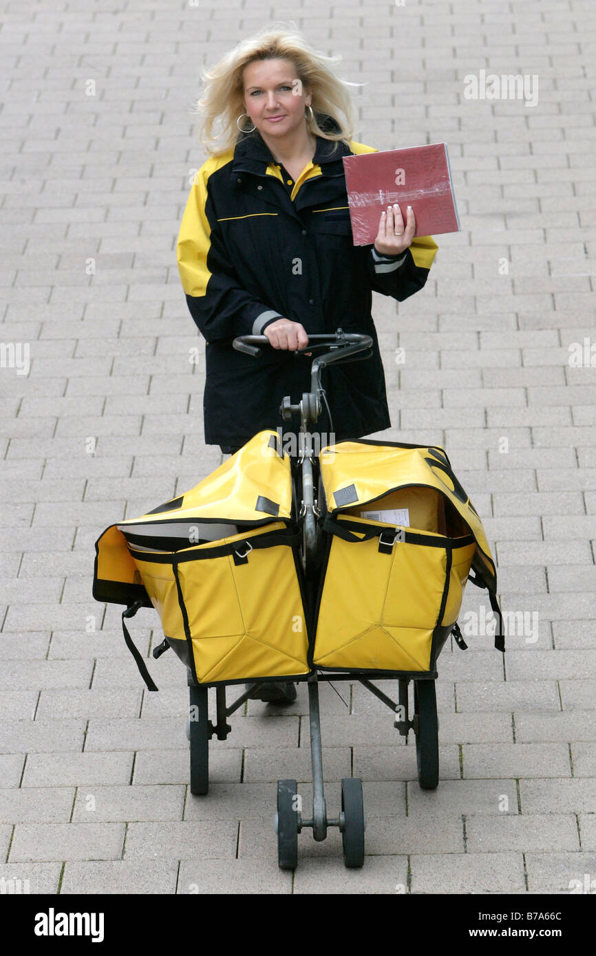 Mailwoman of the Deutsche Post AG, German post, pushing a cart filled ...