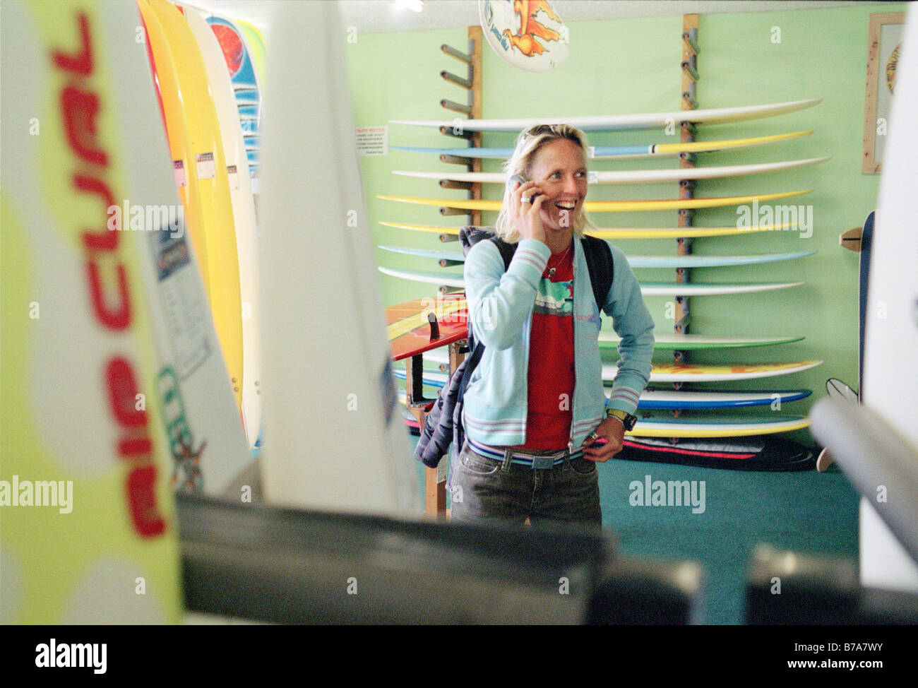 female surfer talking on a mobile phone in a surf board shop selling ...