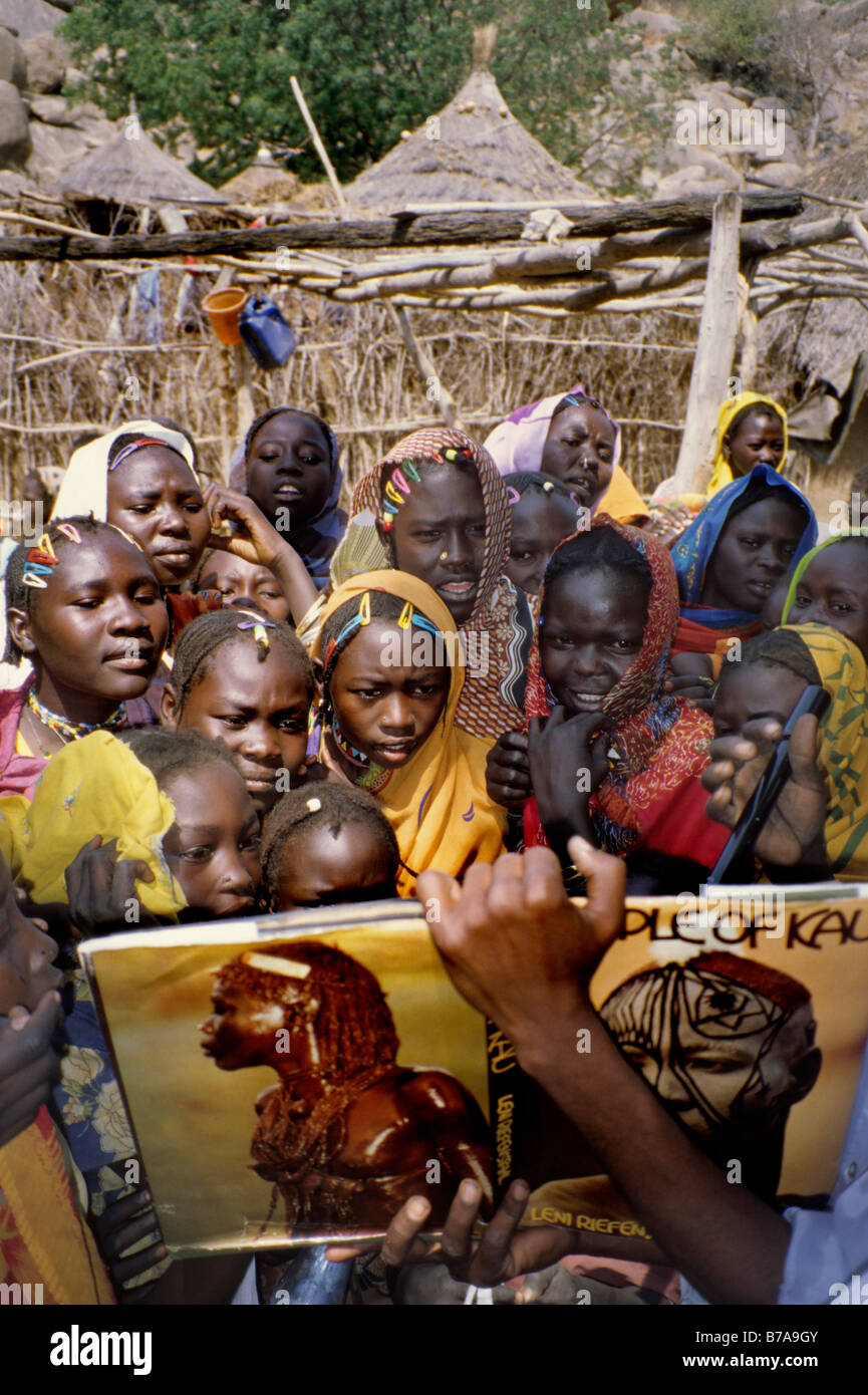 Group of curious children looking at a book by photographer Leni ...