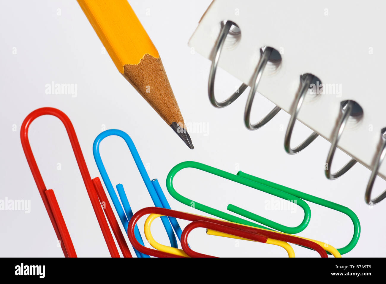 Colored paper clips, pencil and spiral notebook, detail Stock Photo - Alamy