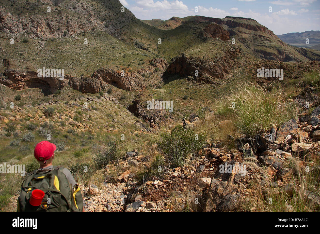 A teenage hiker wearing a red cap on a rocky ridge taking in the view ...