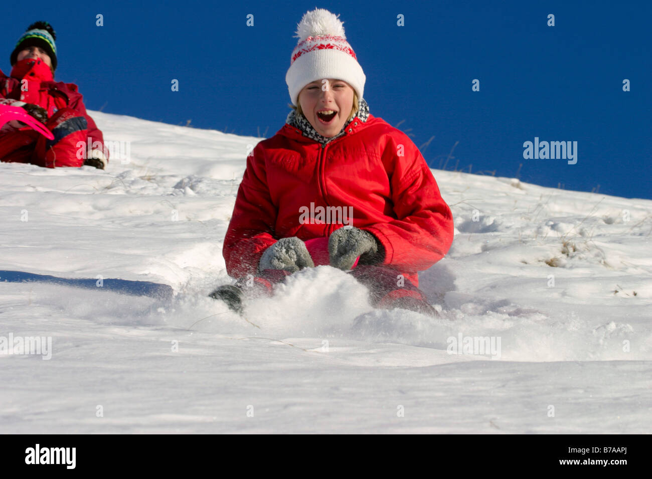 Two girls, 9 and 12 years old, riding on snow-sliders, Dolomites, Italy ...