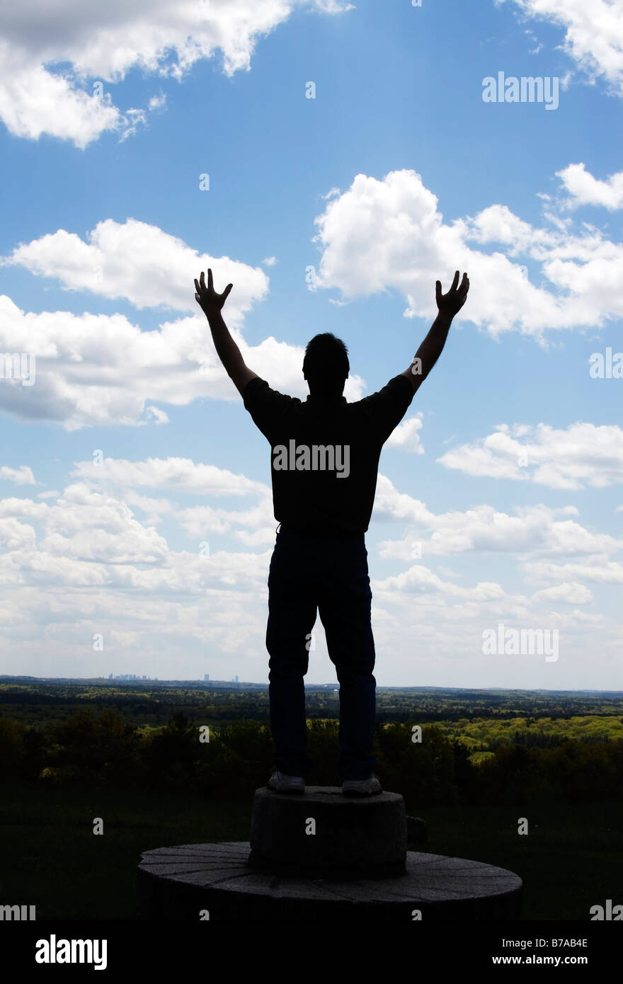 A man standing high up on a hill reaches toward the sky Stock Photo - Alamy